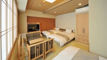 Quarto de hotel com duas camas, televisão, escrivaninha e guarda-roupa.