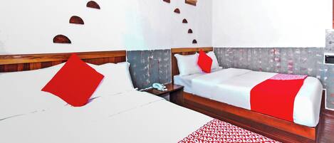 Quarto de hotel com duas camas, cabeceira de madeira, mesa de cabeceira com telefone e luminária fixada na parede.