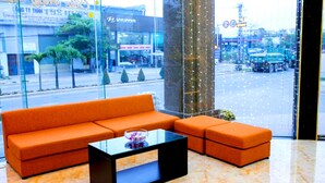 Um lobby moderno com um sofá laranja vibrante e uma mesa de centro de vidro.