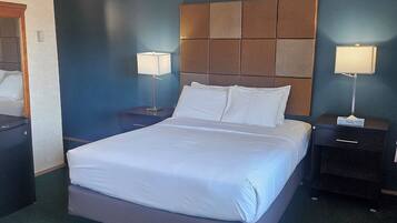 Quarto de hotel com uma cama grande, duas mesas de cabeceira com abajures, uma cabeceira e uma luminária no teto.