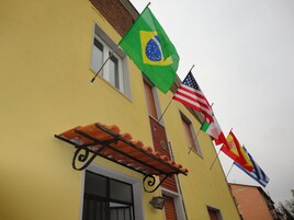 Um edifício com várias bandeiras, incluindo a bandeira do Brasil, e uma varanda com guarda-corpo de metal.