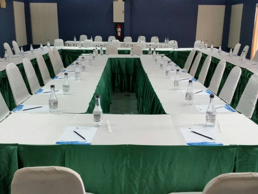 Uma sala de conferências com uma mesa comprida, cadeiras e garrafas de água.
