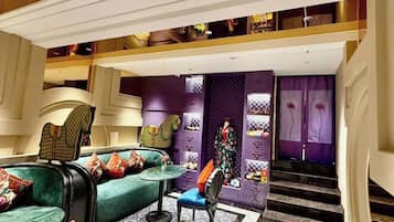 Um hall amplo com piso estampado, uma escada e um espaço de estar com sofá e poltronas.