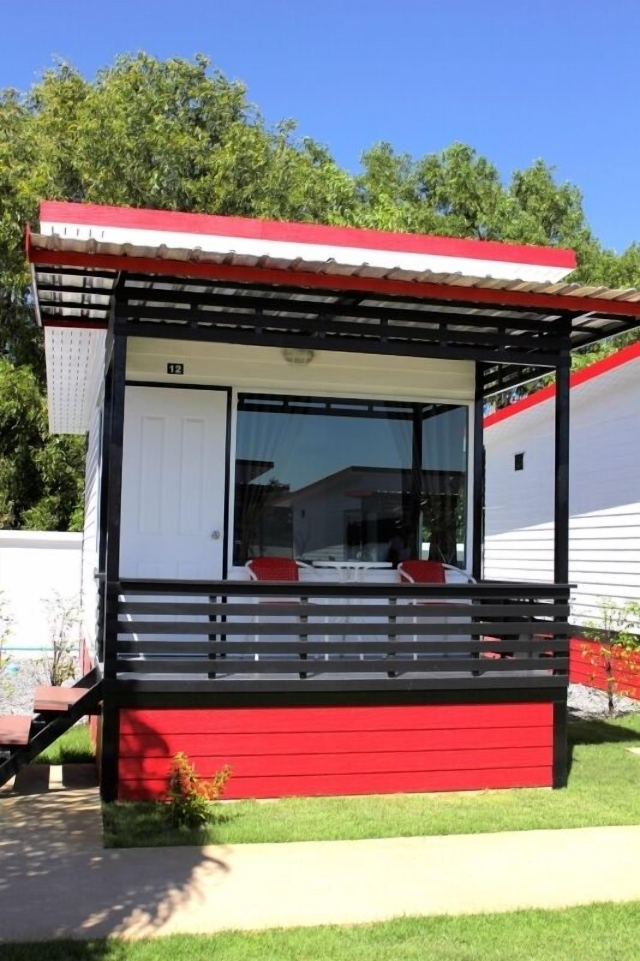 Um pequeno edifício térreo com fachada vermelha e branca, uma porta de vidro e um banco na frente.