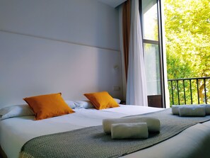 Quarto de hotel com uma cama grande, duas almofadas, um edredom e vista para árvores pela janela.