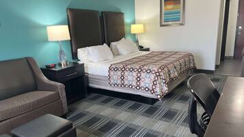 Quarto de hotel com cama, escrivaninha, cadeira e sofá.