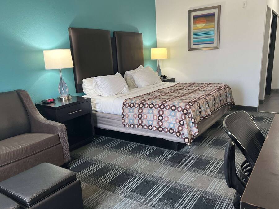 Quarto de hotel com cama, escrivaninha, cadeira e sofá.