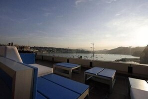 Terraço com mobiliário e vista para um corpo de água.