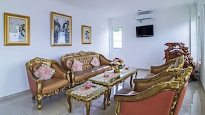 Um quarto com sofá, poltronas, mesa de centro e quadros nas paredes.