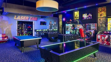 Uma área de jogos com mesa de bilhar, mesa de pebolim e diversos jogos eletrônicos.