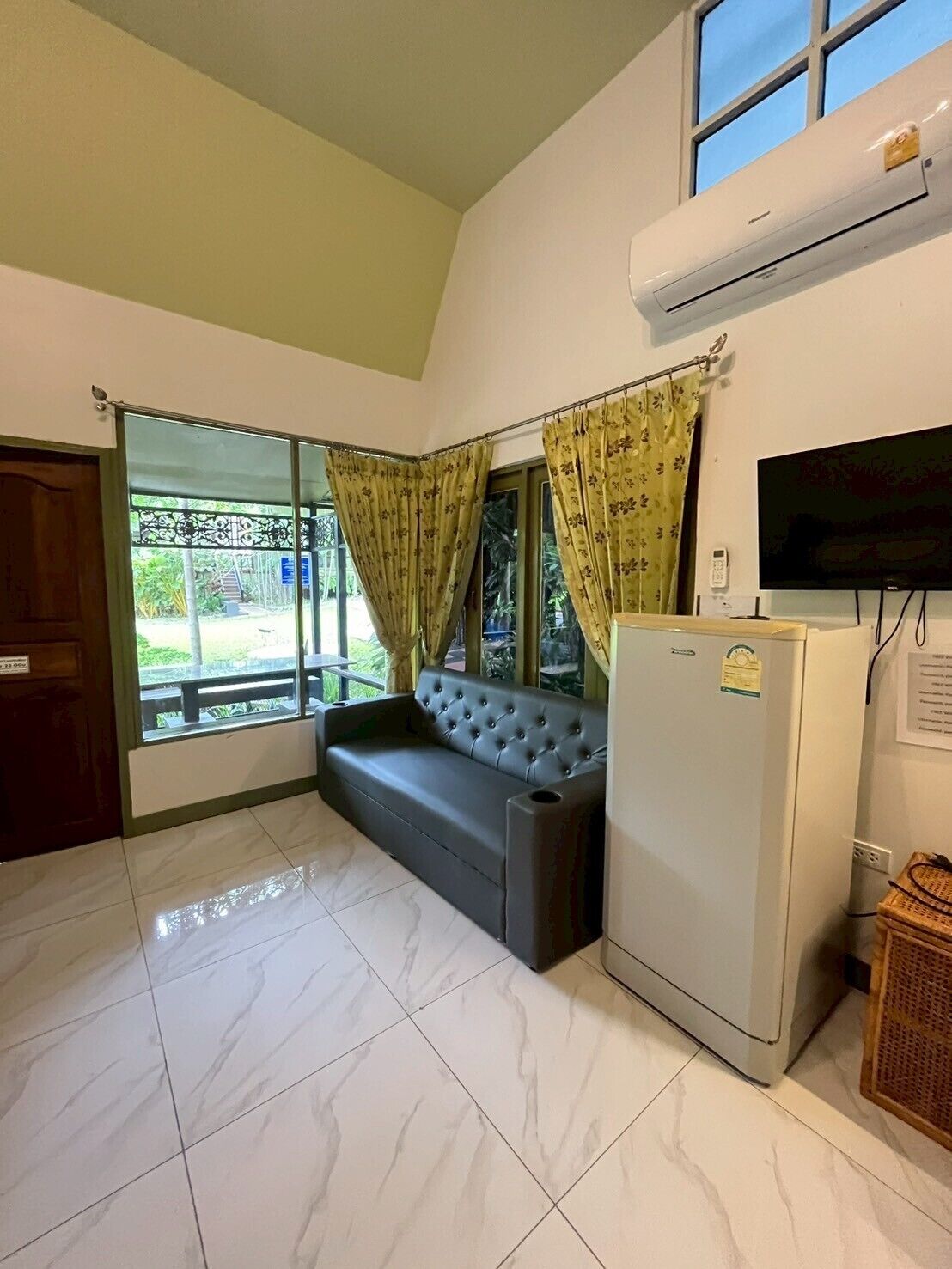 Quarto com sofá, televisão e frigorífico.