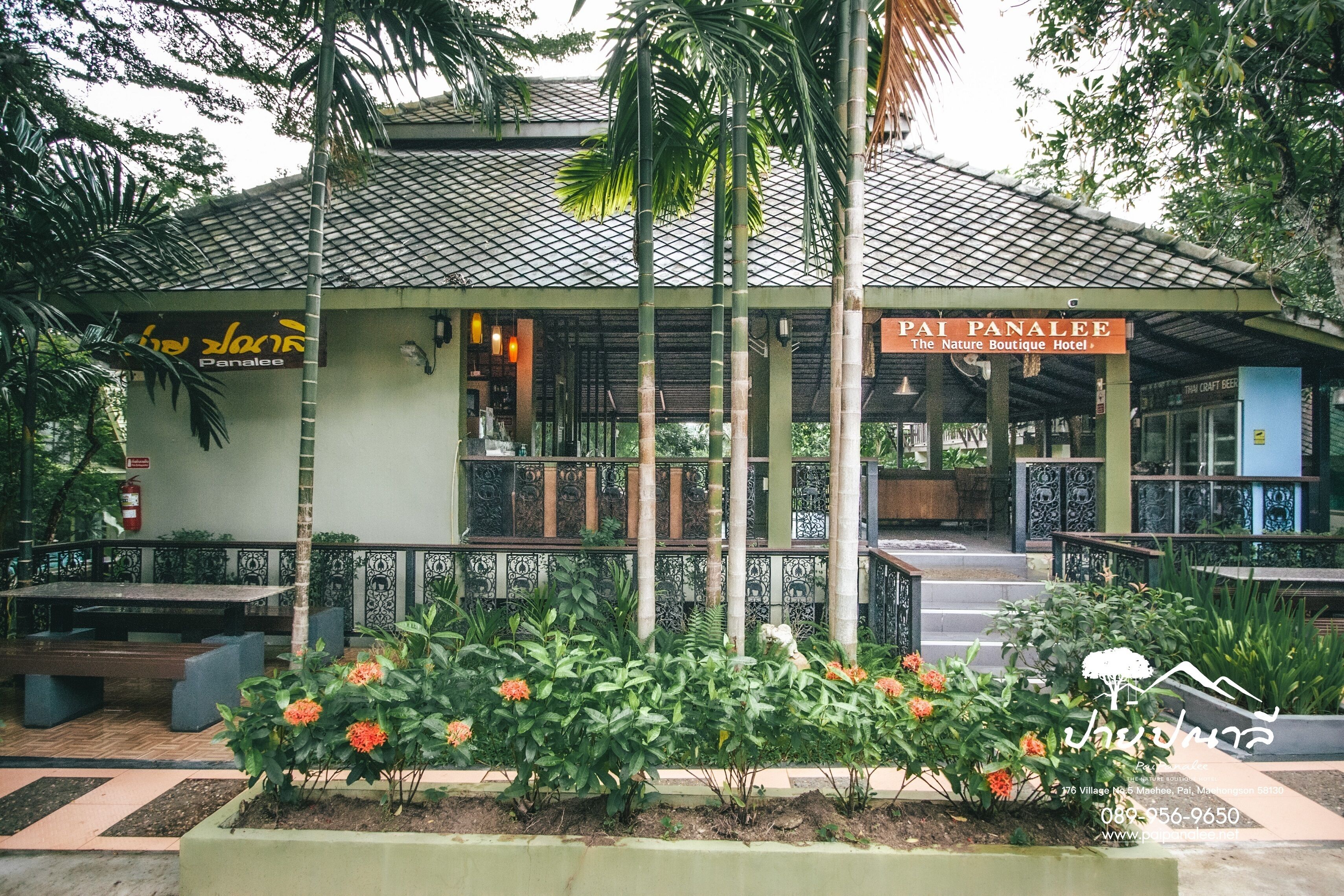 Um hotel com telhado de azulejos, área de estar ao ar livre e uma placa com a inscrição "PAI PANALEE The Nature Boutique Hotel".