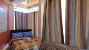 Quarto com cama, sofá e cortinas.