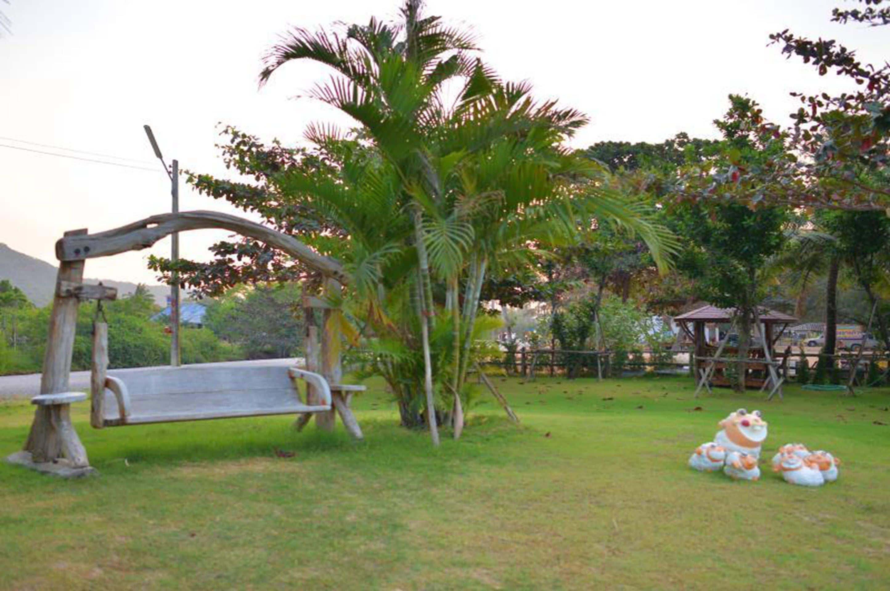 Um parque com baloiço de madeira, um banco e um coreto.