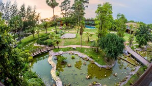 Um jardim ajardinado com lago, palmeiras e uma ponte.