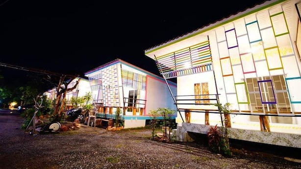 Dois edifícios com desenhos coloridos nas janelas, rodeados por cascalho e pequenas plantas.