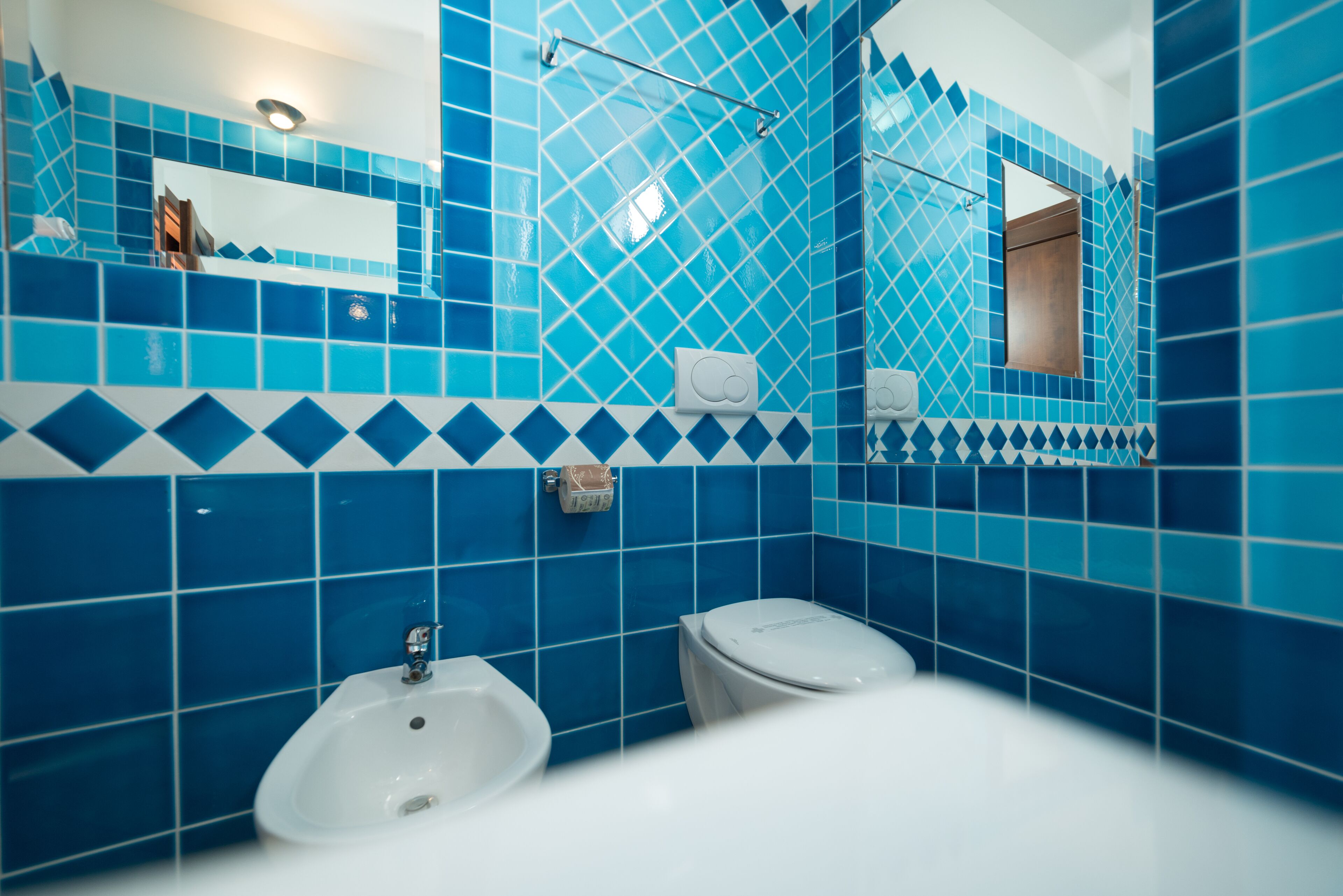 Casa de banho com azulejos azuis, lavatório e sanita.