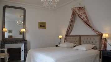 Quarto com cama grande, candelabro, lareira e espelho.