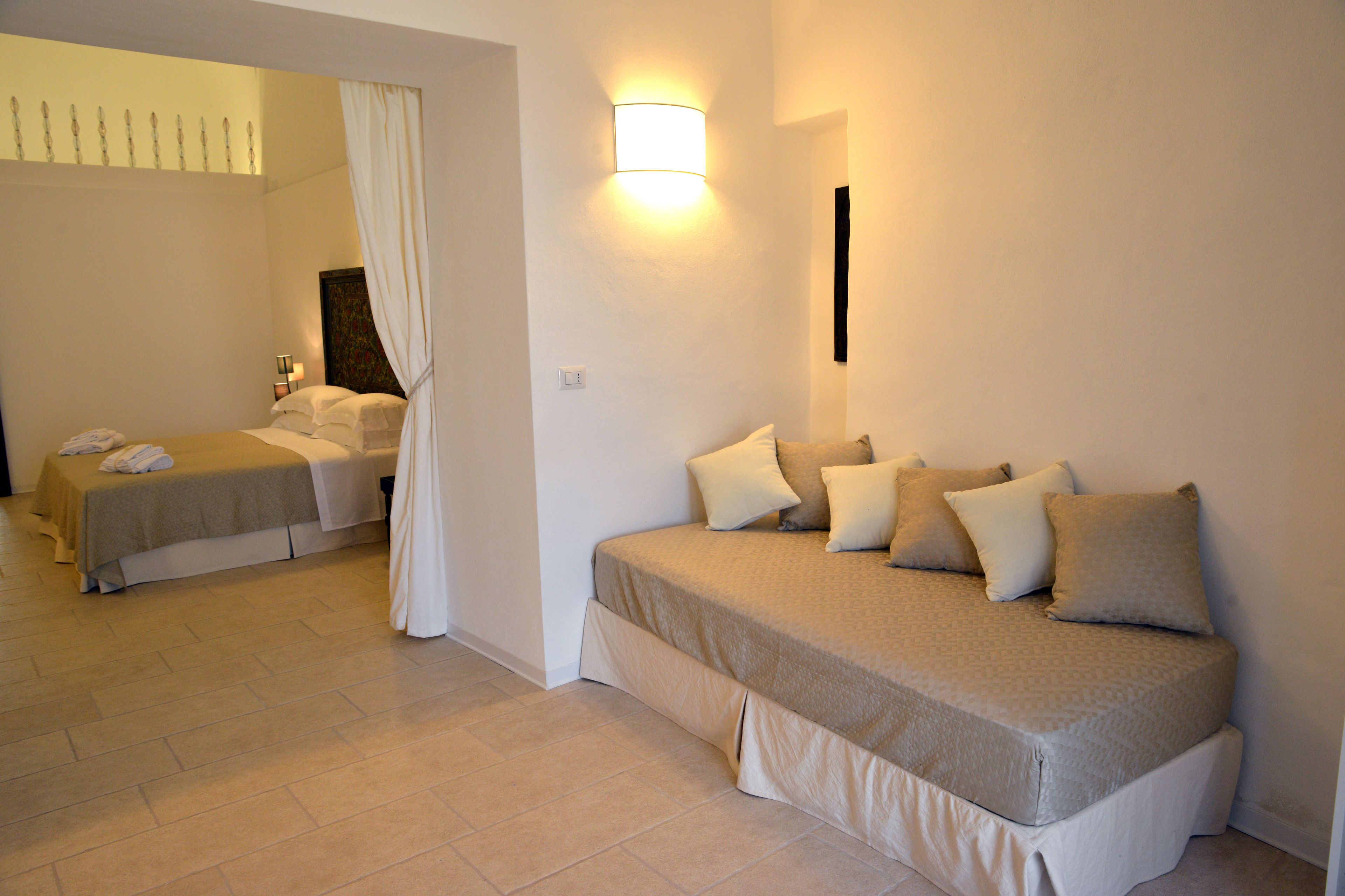 Quarto de hotel com duas camas, um espelho grande, uma luminária fixada na parede e uma porta com cortina.