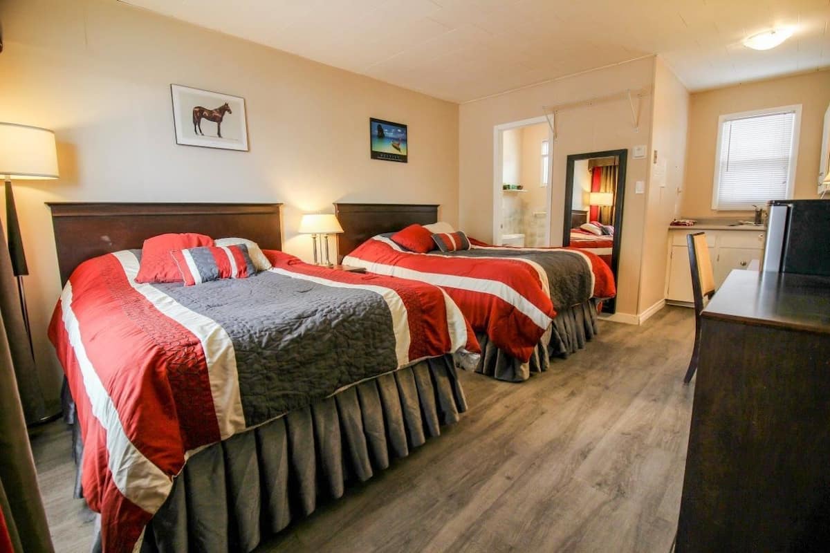 Quarto de hotel com duas camas, uma mesa e um espelho.