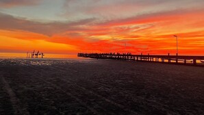 Uma praia com um píer que se estende para a água ao pôr do sol.