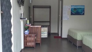 Quarto de hotel com cama, televisão na parede, pequena escrivaninha com cadeira, frigorífico e porta com cortina.