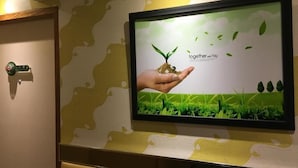 Um quadro emoldurado mostrando uma mão segurando terra com um broto e o texto "together with You" em uma parede com padrão amarelo e branco.