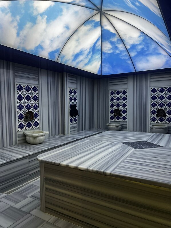 Quarto com uma cama grande, um espaço de estar pequeno e vista do céu através de um design no teto.