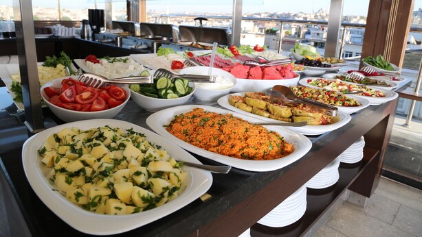 Buffet com diversos pratos, incluindo saladas, frutas e comidas quentes.