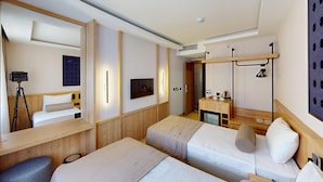 Quarto de hotel com duas camas, uma escrivaninha, um espelho, uma televisão e uma pequena cozinha equipada.