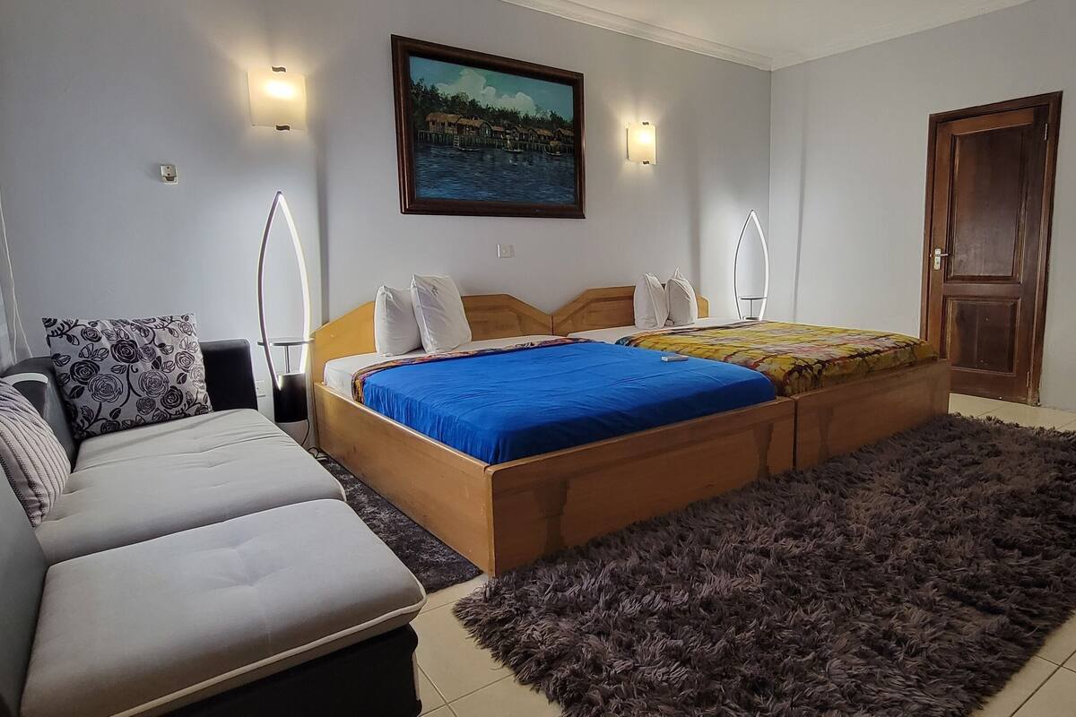 Um quarto com cama, sofá, tapete, quadro e espelho.