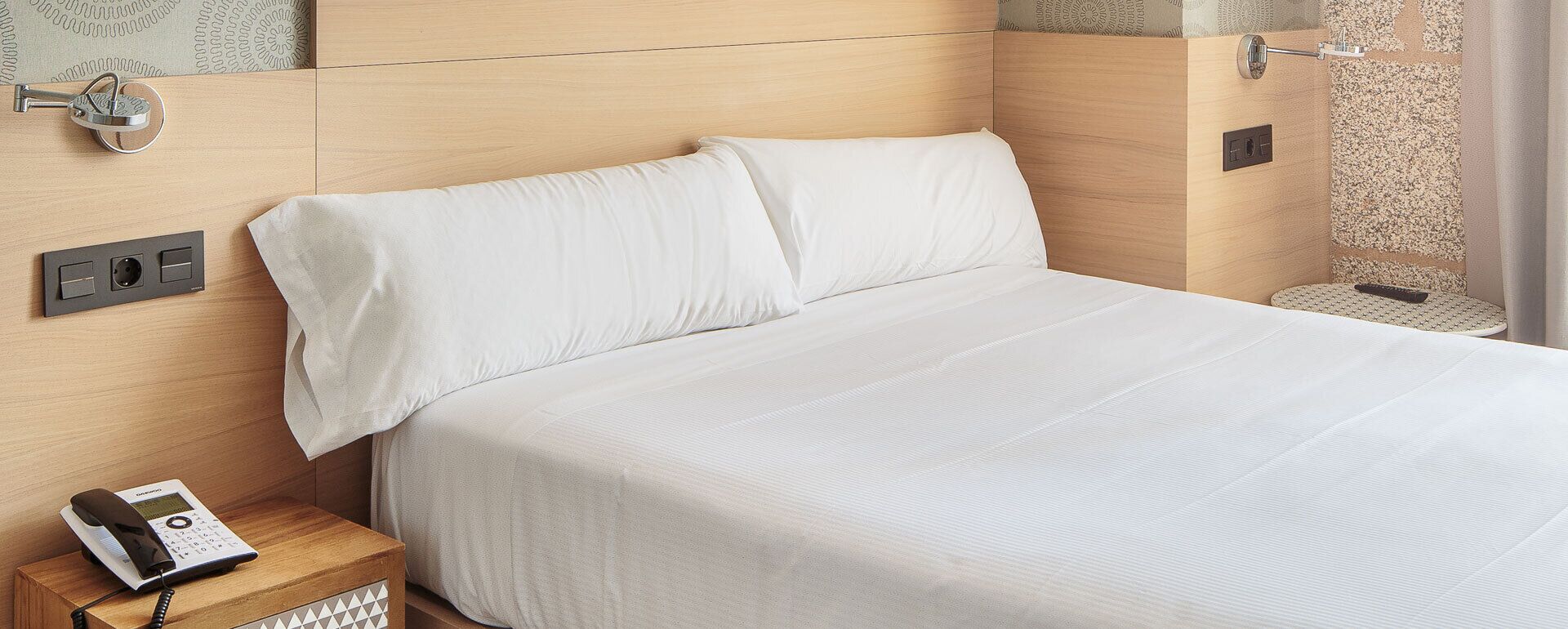 Quarto de hotel com cama, telefone ao lado da cama e área de chuveiro.
