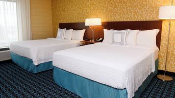 Quarto de hotel com duas camas, carpete estampado e parede decorada.