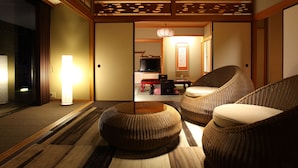 Um quarto japonês tradicional, com piso de tatame, teto de madeira baixo e uma porta deslizante para uma sala de jantar.