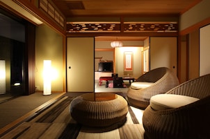 Um quarto japonês tradicional, com piso de tatame, teto de madeira baixo e uma porta deslizante para uma sala de jantar.