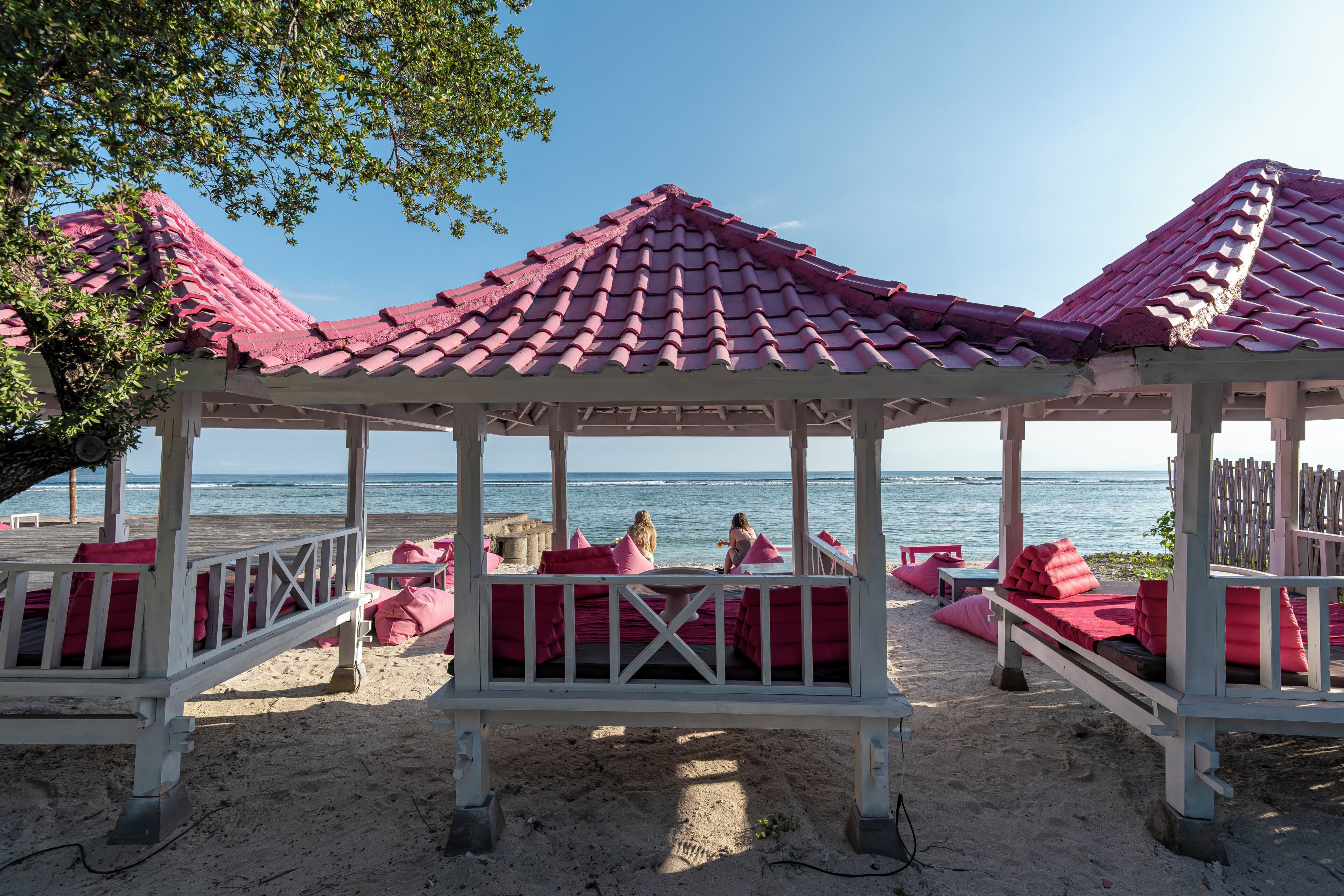 Um gazebo à beira-mar com assentos e vista para o mar.