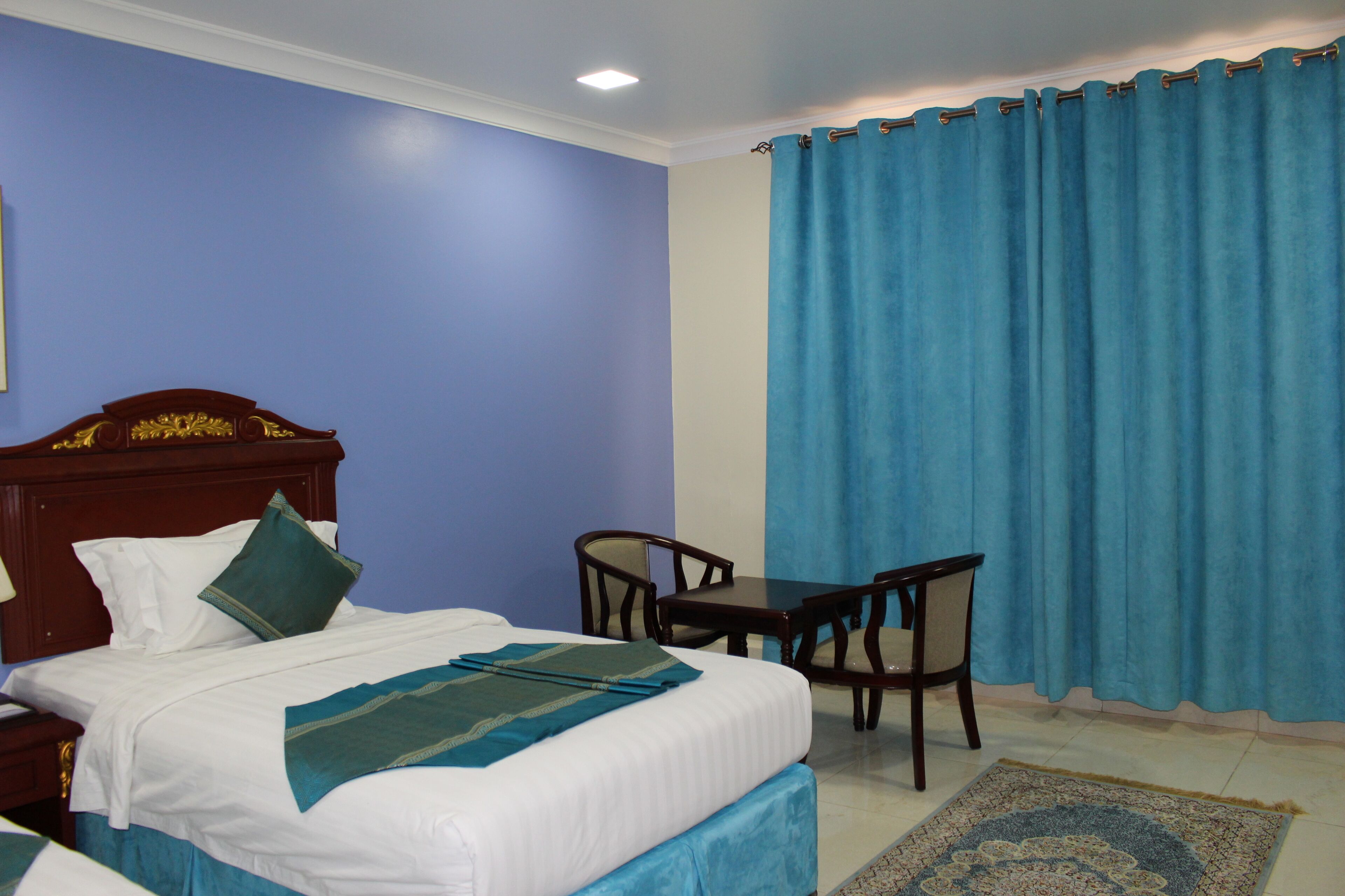 Quarto de hotel com cama, escrivaninha e cadeira.