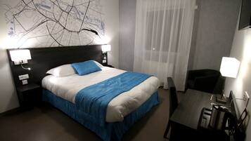 Quarto de hotel com cama, escrivaninha, cadeira e mapa na parede.