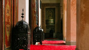 Um corredor com lustres negros ornamentados e tapete vermelho.