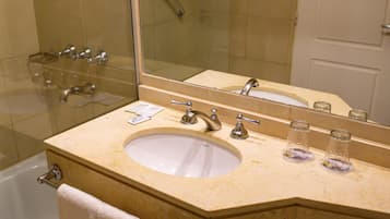 Casa de banho com lavatório, espelho e cabine de duche em vidro.