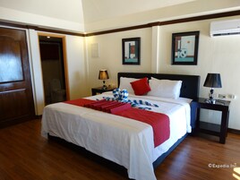 Quarto de hotel com cama grande, mesa de cabeceira, abajur e quadro na parede.