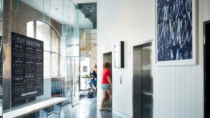 Um interior moderno com uma parede de vidro exibindo sugestões da equipe, um banco e um elevador.