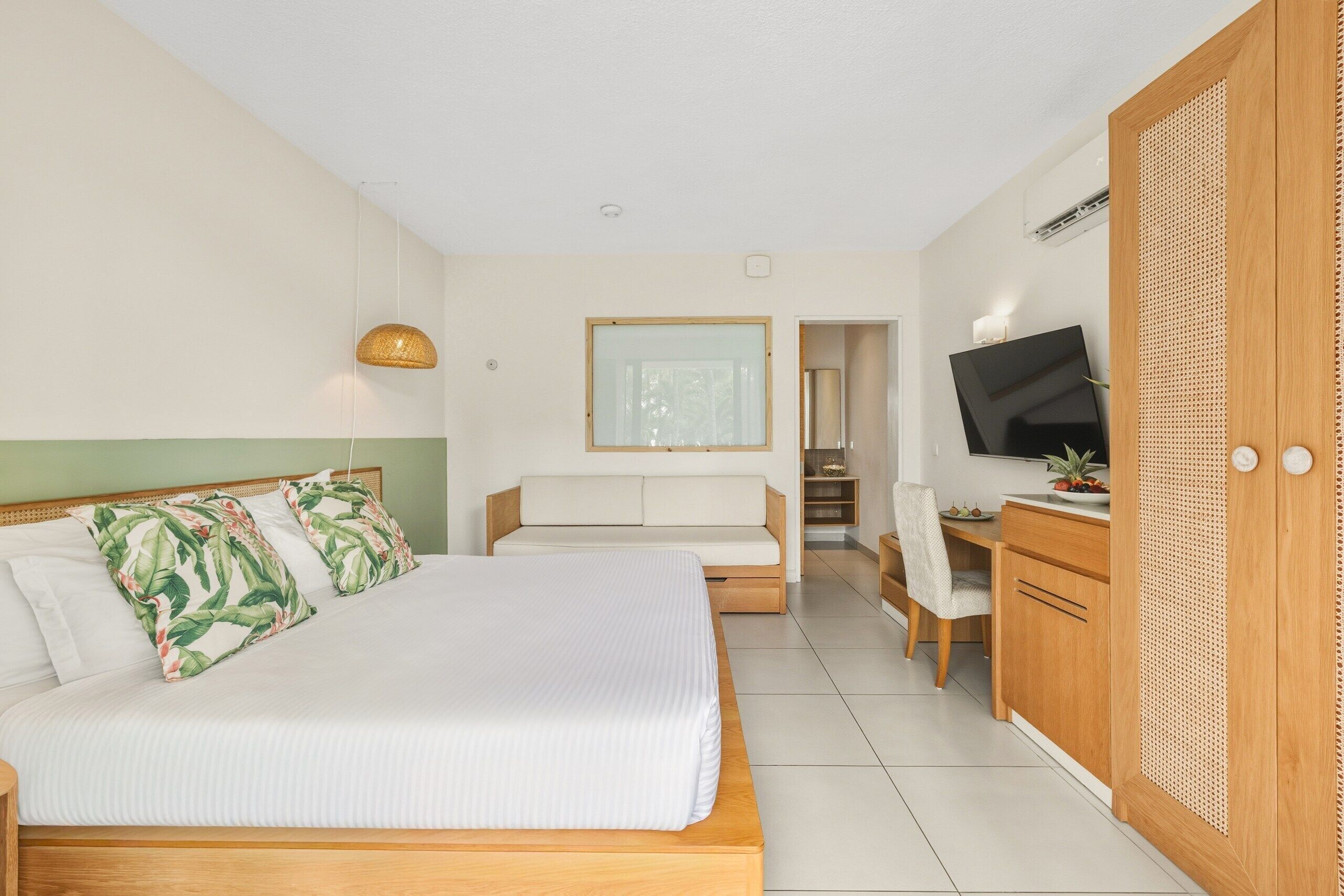 Quarto moderno com uma cama grande, escrivaninha, televisão e guarda-roupa.