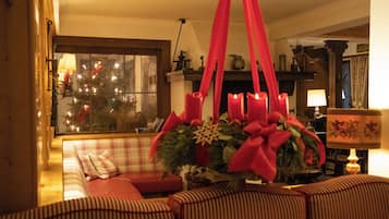 Uma sala de estar acolhedora com lareira, árvore de Natal e uma guirlanda grande sobre uma mesa.