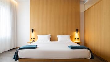 Quarto de hotel moderno com cama grande, cabeceira de madeira e abajures laterais.