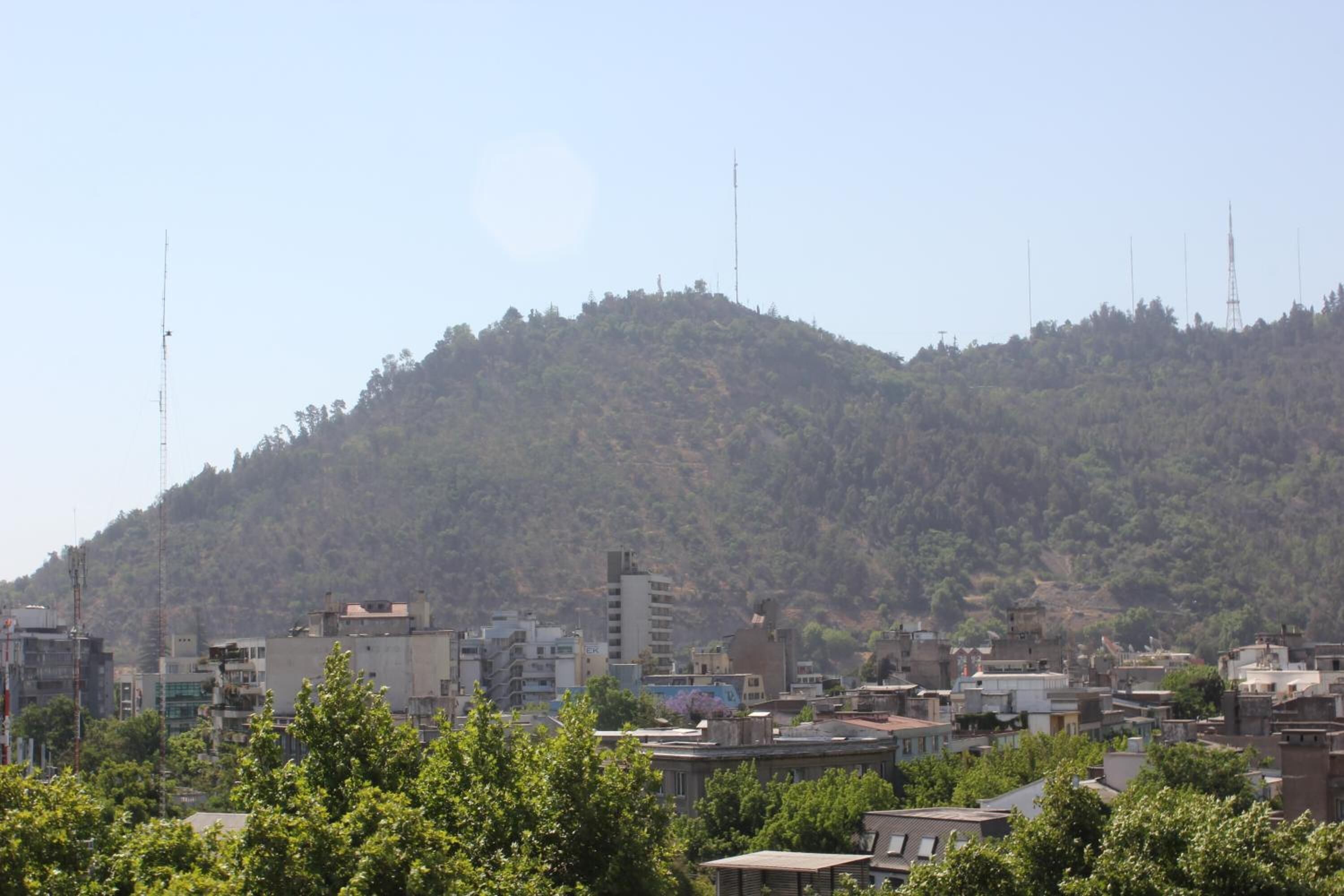 Paisagem urbana com edifícios e uma colina ao fundo.