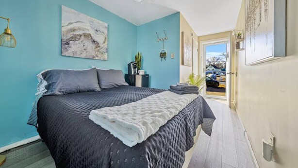 Quarto com cama grande, ventilador de teto, um quadro e vista para o exterior.