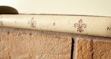 Close-up de um canto de parede com moldura decorativa com motivos de flor-de-lis.