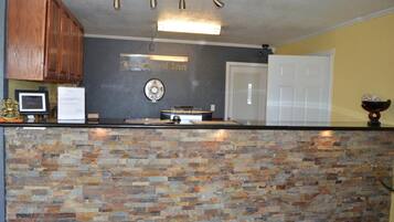 Uma cozinha com painel de pedra, armários de madeira, um relógio e uma placa com 'The Old Inn'.