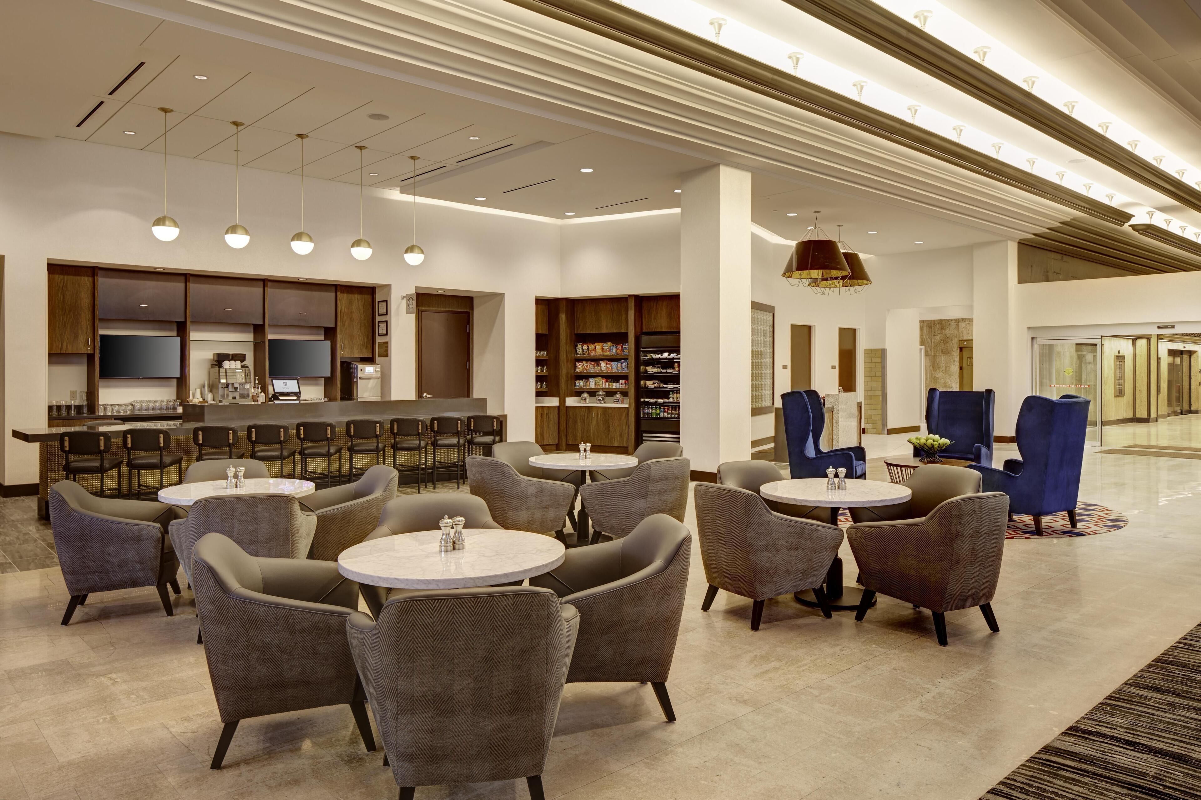 Um hall de hotel moderno com área de bar, assentos e balcão de recepção.